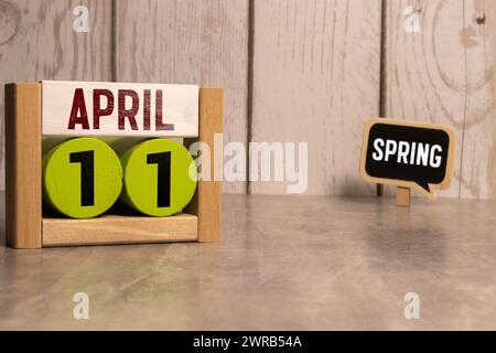 April 11 calendar date text on white wooden block with stationeries on ...