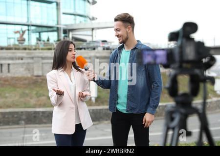 Young journalist interviewing businesswoman on city street Stock Photo ...