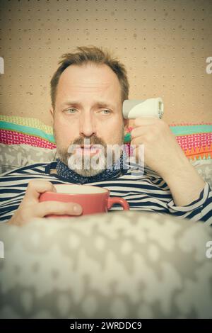 Mature sick man checking body temperature with thermometer Stock Photo ...