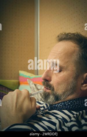 Mature sick man checking body temperature with thermometer Stock Photo ...