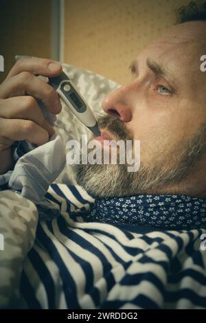 Mature sick man checking body temperature with thermometer Stock Photo ...