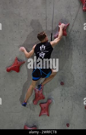 Young speed climber climbs up the vertical wall at a professional ...