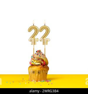 Cupcake with number 22 birthday candle - White block wall background ...