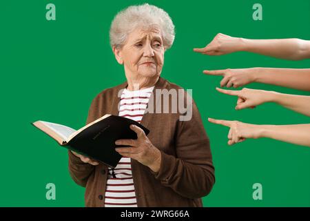 People pointing at senior woman with Holy Bible on green background ...