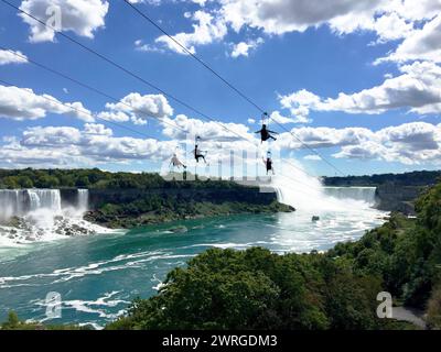 Riders gliding on the zipline to the falls at Niagara Falls, Ontario ...