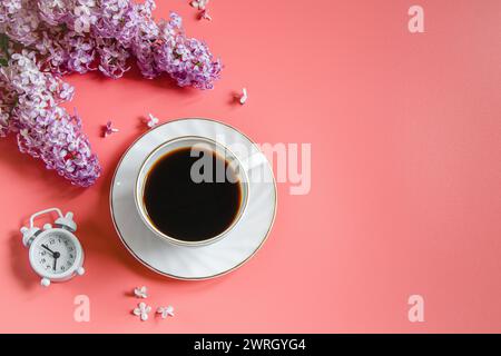 Alarm clock, lilac flowers and cup of coffee on light background ...