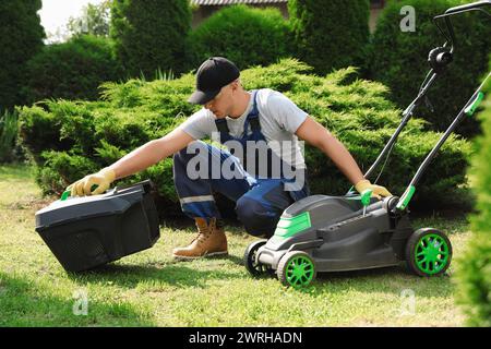 Cleaning lawn mower. Young man detaching grass catcher from device in ...