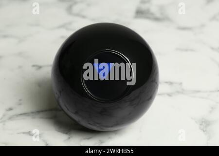 Magic eight ball on white wooden table and positive predictions around ...