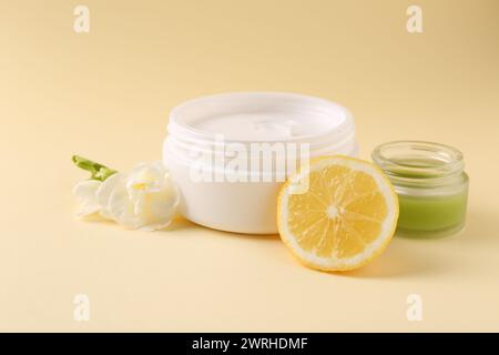 Moisturizing cream in open jars, soap bars and freesia flower on beige ...