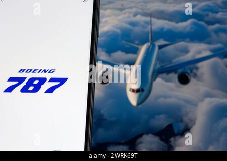 Boeing 787 logo is sharp in the foreground, while flying airplane is ...