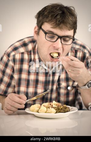 Man eating his lunch made of baked rabbit meat and gnocchi Stock Photo ...
