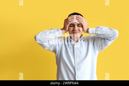 Young man with brain concussion and bandaged head on yellow background ...