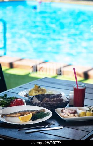 Fried grayling fish on a plate with any appetizers on swimming pool ...