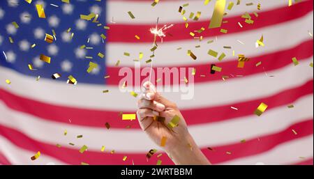 Image of confetti falling over hand holding flag of united states of ...