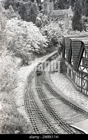 1970s, historical, a model railway in a back garden, showing a raised ...