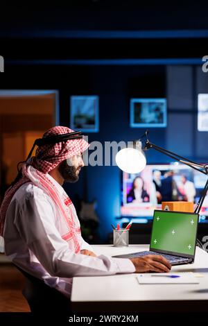 Image portrays Muslim guy seated at his workstation at home, his ...