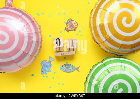 Calendar with balloons, paper fishes and confetti on yellow background ...