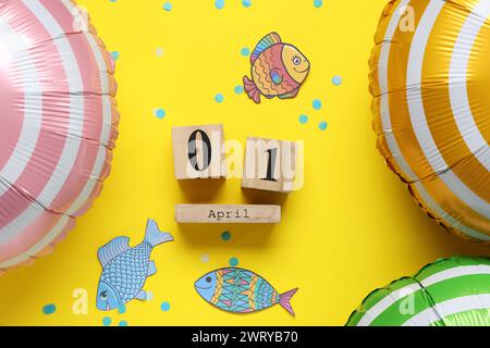 Calendar with balloons, paper fishes and confetti on yellow background ...