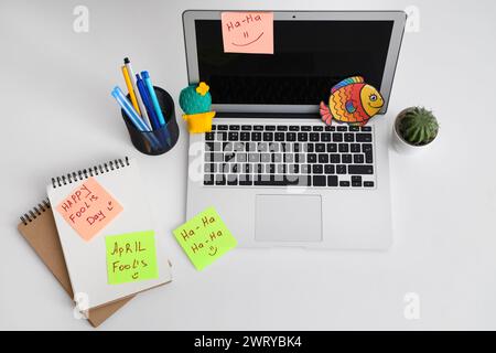 Workspace with laptop, funny sticky notes and paper fish on white ...