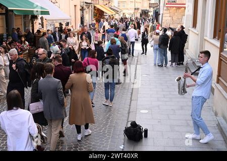 A street musician performs as people walk past, against the backdrop of ...