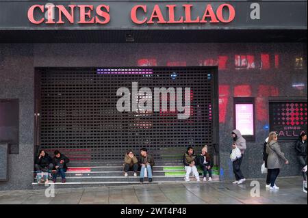 People sit outside a closed cinema theater, Cines Callao, in Madrid ...