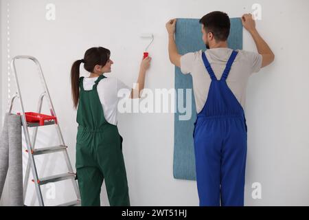 Workers hanging light blue wallpaper in room Stock Photo - Alamy