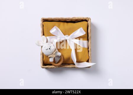 Baby accessory. Rattle and child`s clothes in wicker box on white ...