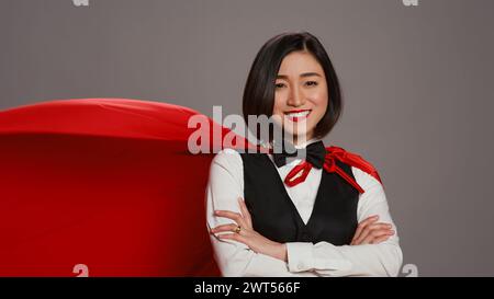 Asian receptionist posing with red superhero cape on camera, feeling ...