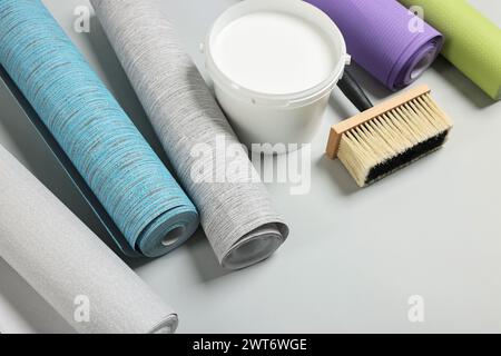 Different wallpaper rolls, brush and bucket with glue on light ...