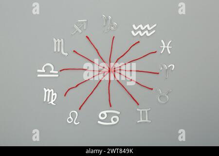 Zodiac compatibility. Signs, red threads and wedding rings on grey ...