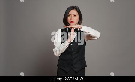 Asian receptionist expressing timeout symbol on camera, showing ...