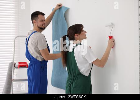 Workers hanging light blue wallpaper in room Stock Photo - Alamy