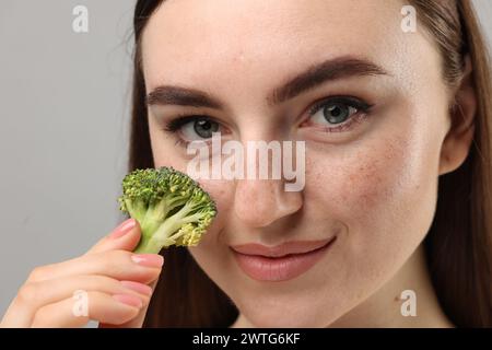 Beautiful woman making fake freckles with broccoli and cosmetic product ...