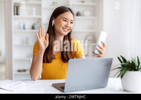 Asian woman waving hand during video call on tablet at home Stock Photo ...