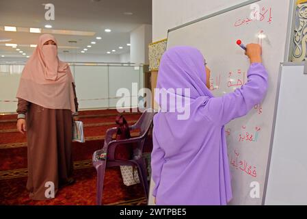 An Arabic teacher wearing an Islamic veil corrects a text in Arabic ...