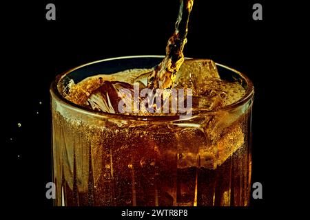 Soda, coke, dark beer pouring from bottle into glass against black background Stock Photo - Alamy