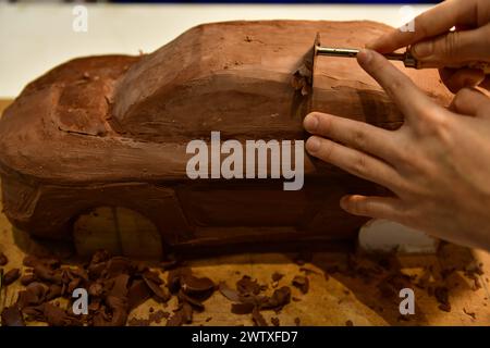 Designers work on the car's sculpture using carving tools. Adjust the ...