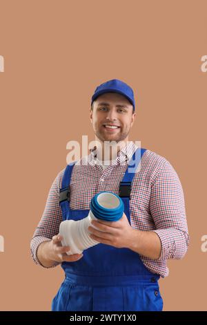 Male plumber with pipe on brown background Stock Photo - Alamy