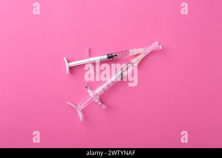 Injection cosmetology. Two medical syringes on pink background, top ...