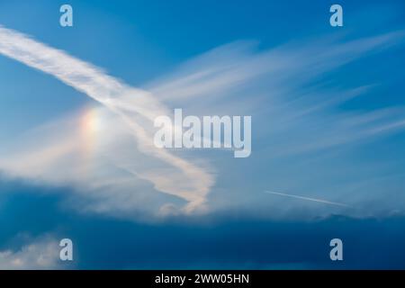 Sky with cirrus, stratus clouds, airplane trail and halo from the sun ...