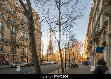 The Eiffel Tower peeks between trees along Avenue de la Bourdonnais at ...