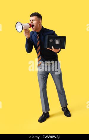 Young man with safe box and megaphone screaming on grey background ...
