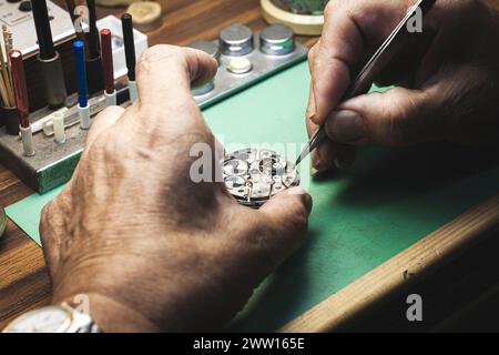 The hands of a watchmaker repairing a watch. They are manipulating a ...