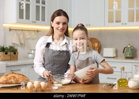 Making bread. Mother and her daughter preparing dough at wooden table ...