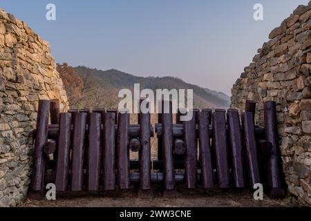 Wooden log blockade at gate of mountain fortress made of flat stones in ...