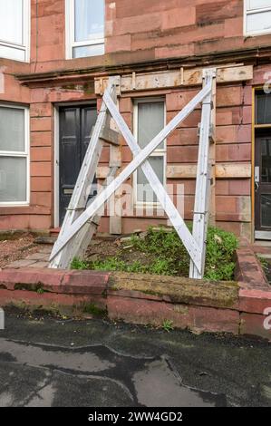 A damaged tenement block supported on the ground floor by an extenal ...