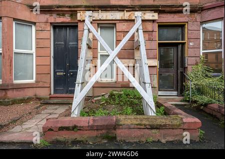 A damaged tenement block supported on the ground floor by an extenal ...