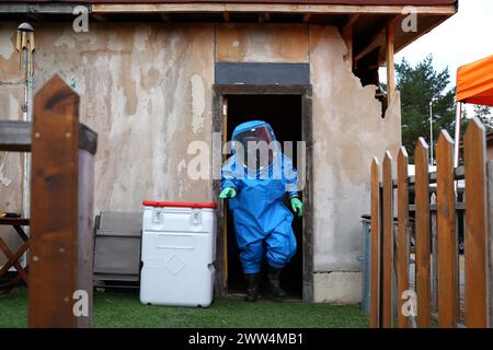 Person wears blue Personal protective equipment (PPE) with gas mask for ...