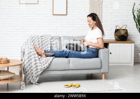 Beautiful mature woman with sticks playing glucophone on sofa at home ...