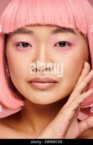 Asian girl with pink hair and piercing frowning while looking aside ...